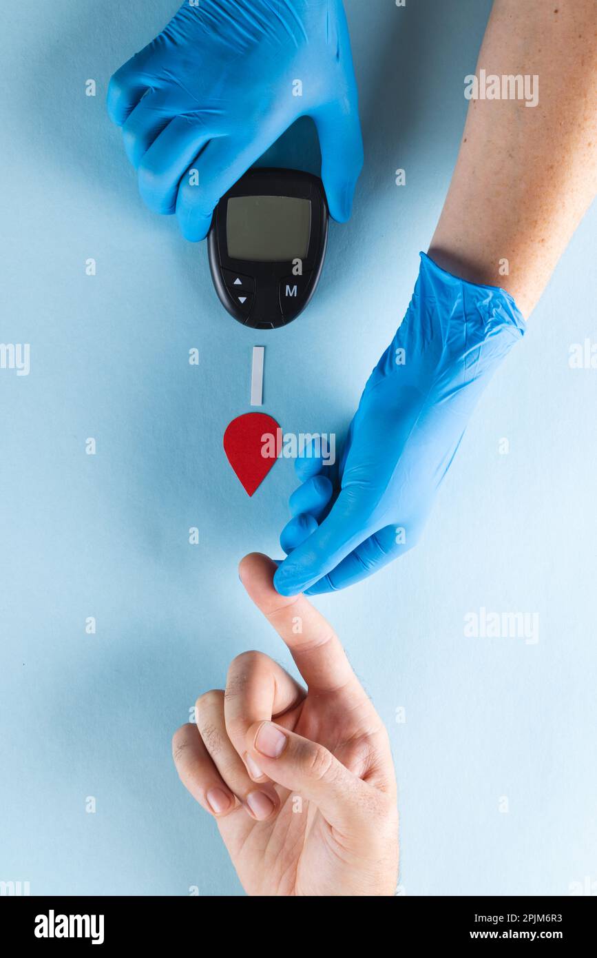 Hands of gloved doctor with glucometer taking blood sugar reading from ...