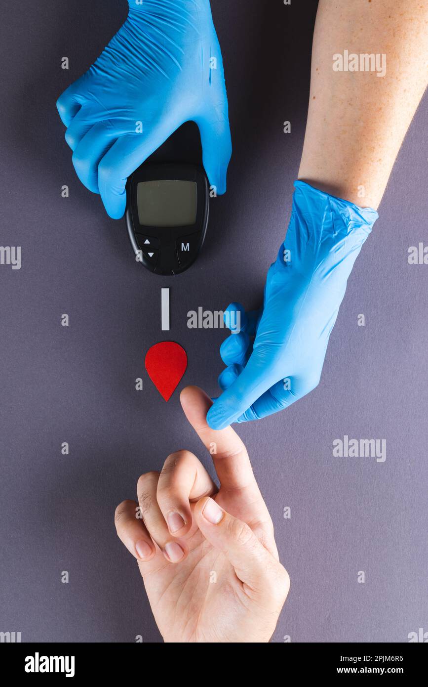 Hands of gloved doctor with glucometer taking blood sugar reading from ...