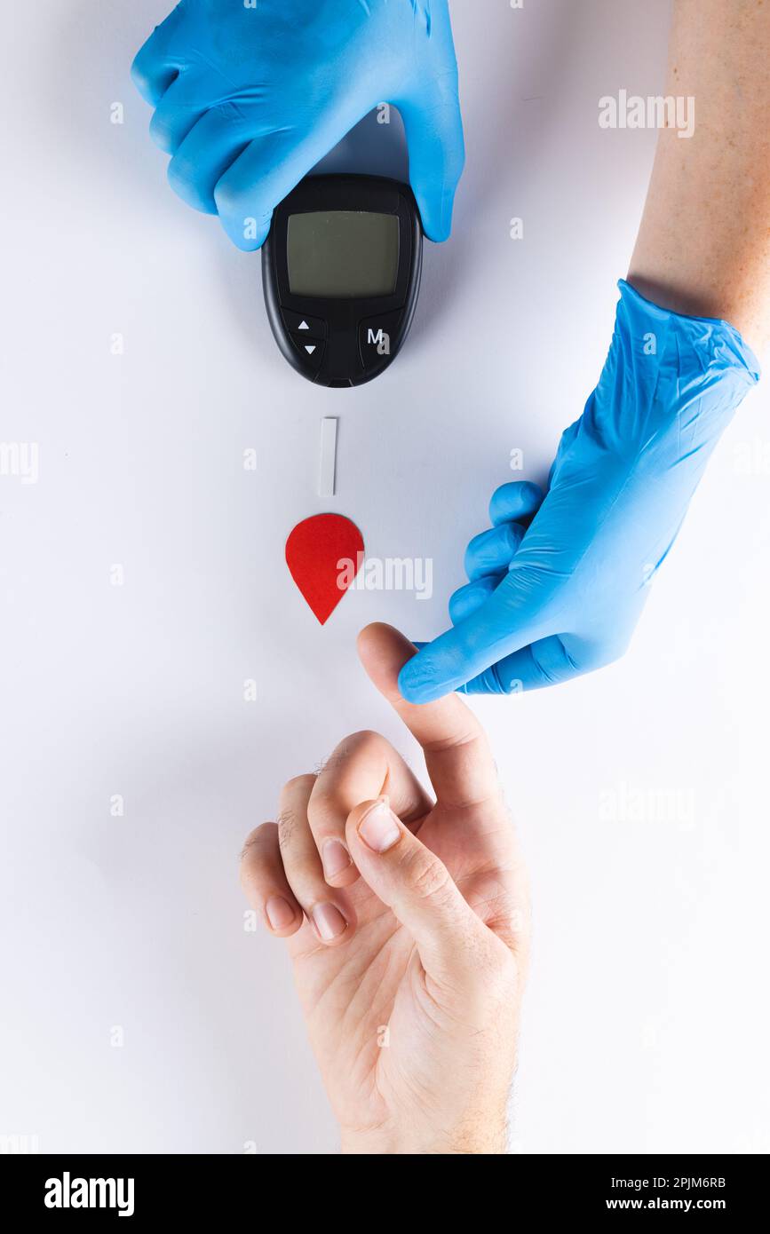 Hands of gloved doctor with glucometer taking blood sugar reading from ...