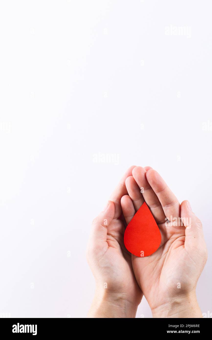 Hands of caucasian woman cupping blood drop, on white background with ...