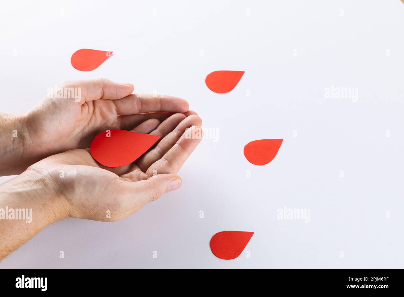 Hands of caucasian woman cupping blood drop, with blood drops on white ...