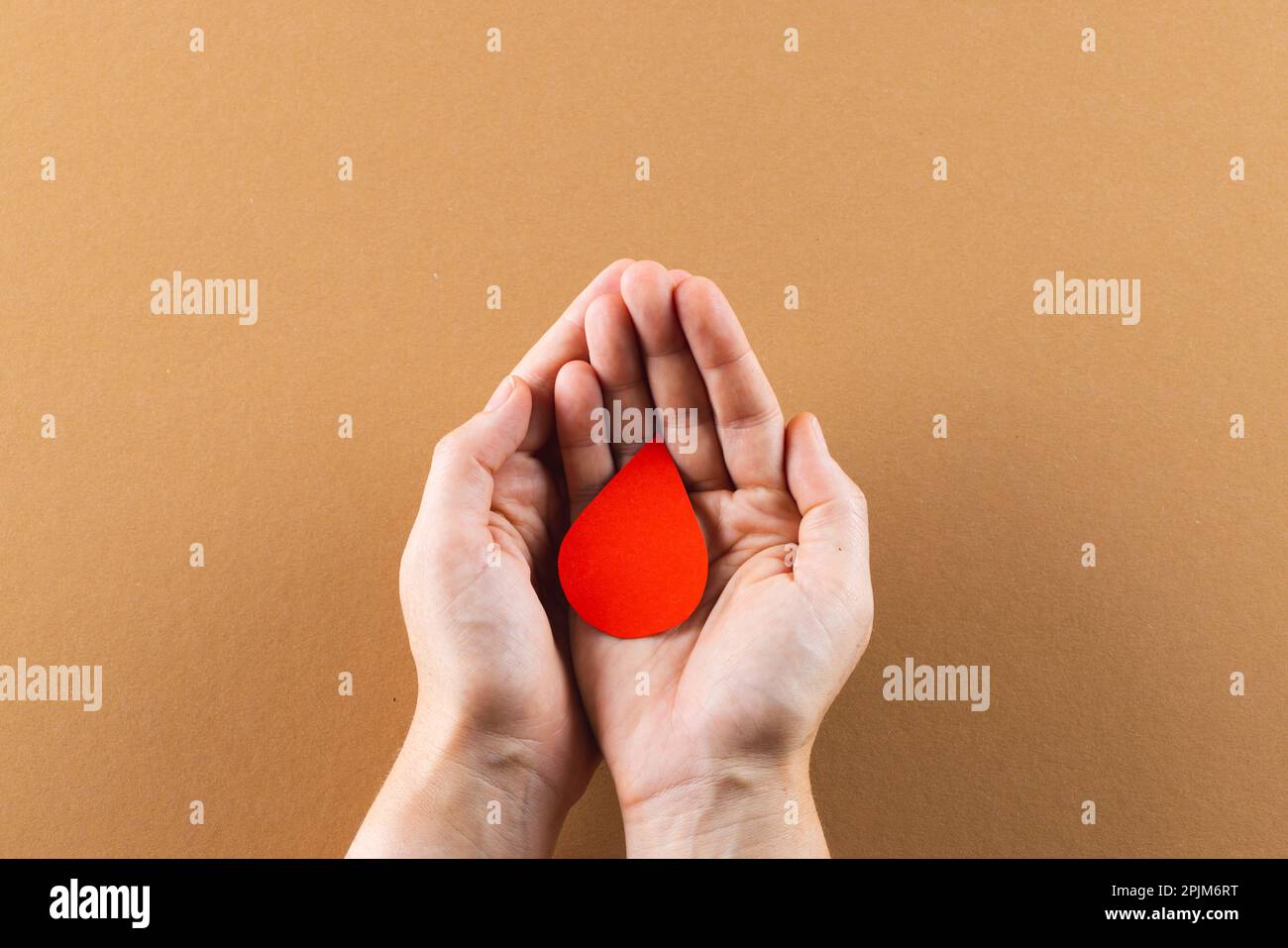 Hands of caucasian woman cupping blood drop on brown background Stock ...
