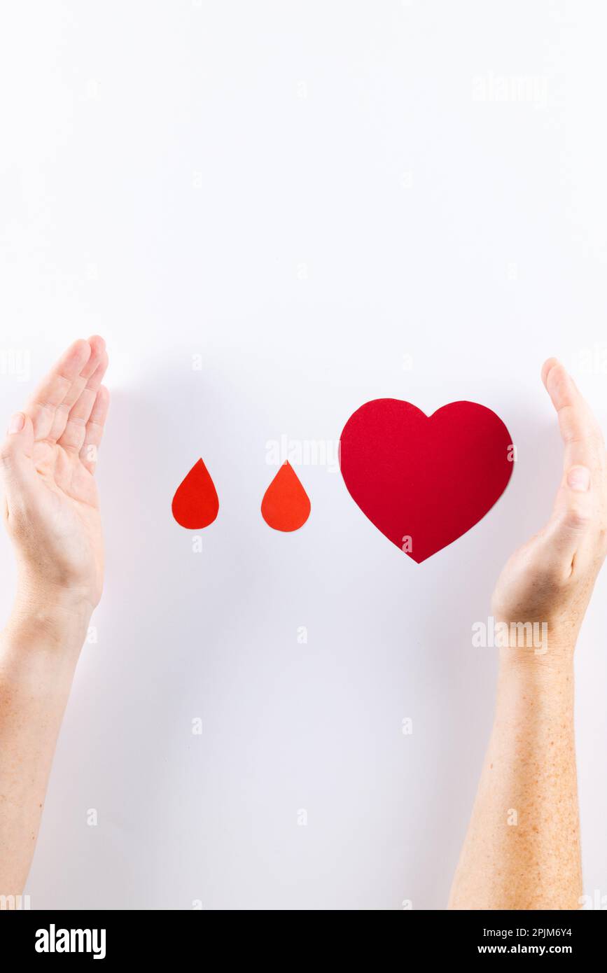 Hands of caucasian woman protecting blood drops and heart on white ...