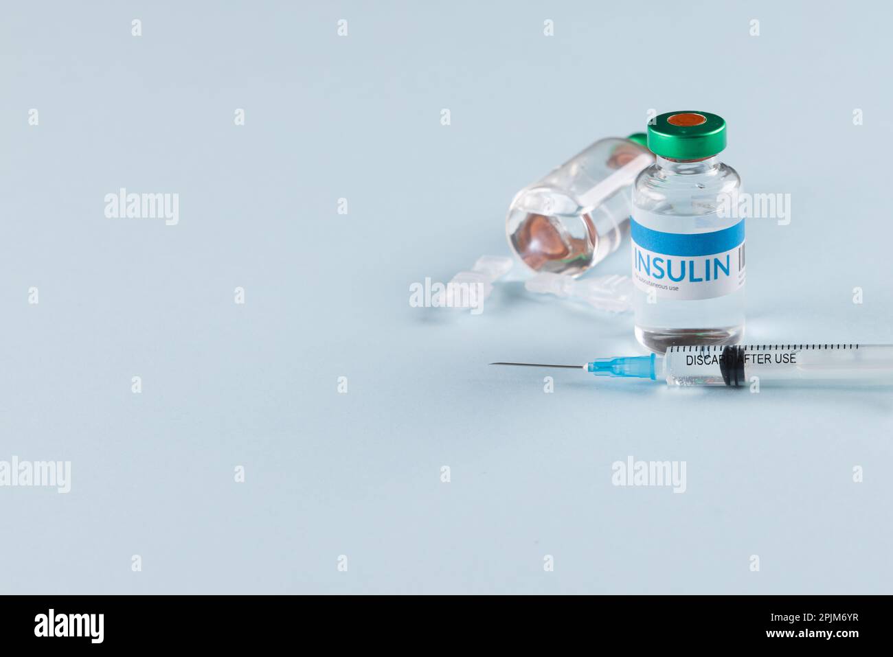 Vials of insulin with caplets and syringe on blue background with copy ...