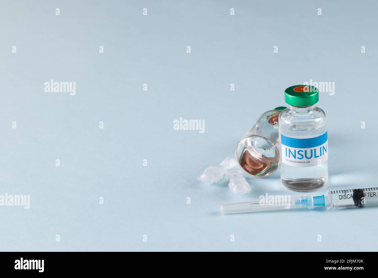 Vials of insulin with caplets and syringe on blue background with copy ...