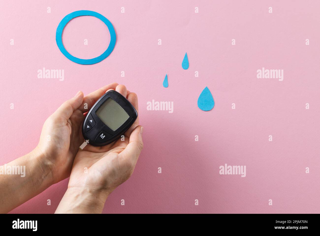 Hands of caucasian woman holding glucometer over blue drops and ring on ...