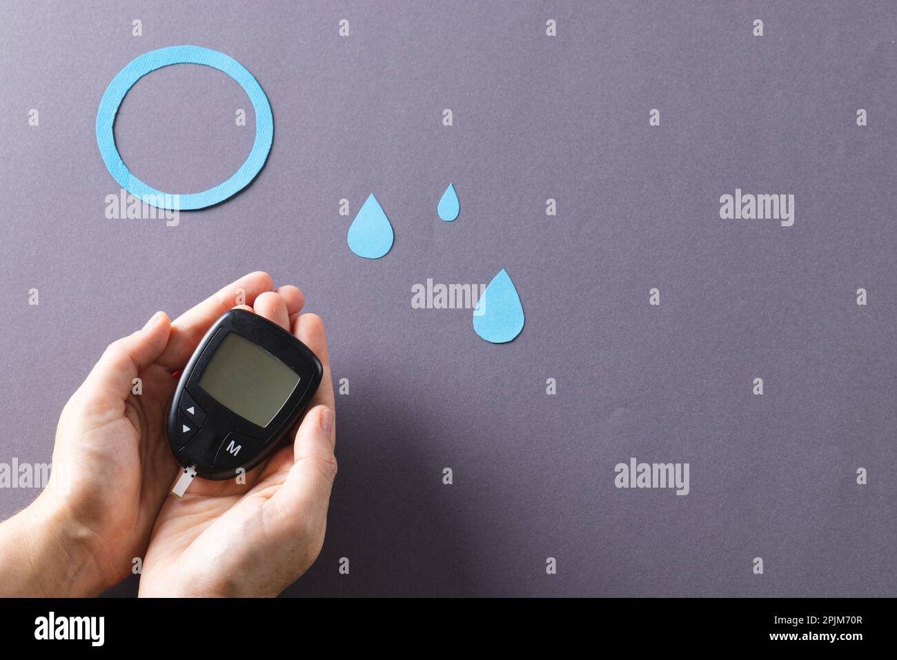 Hands of caucasian woman holding glucometer over blue drops and ring on ...