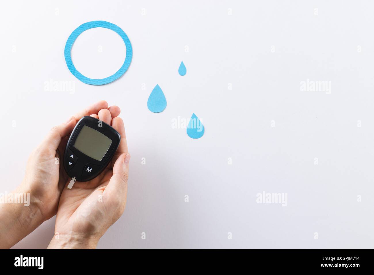 Hands of caucasian woman holding glucometer over blue drops and ring on ...