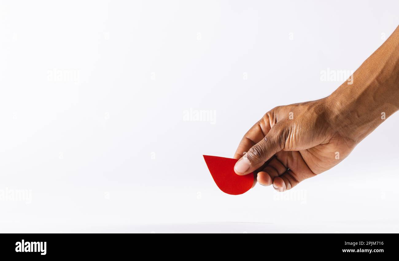 Hand of biracial man holding blood drop, on white background with copy ...