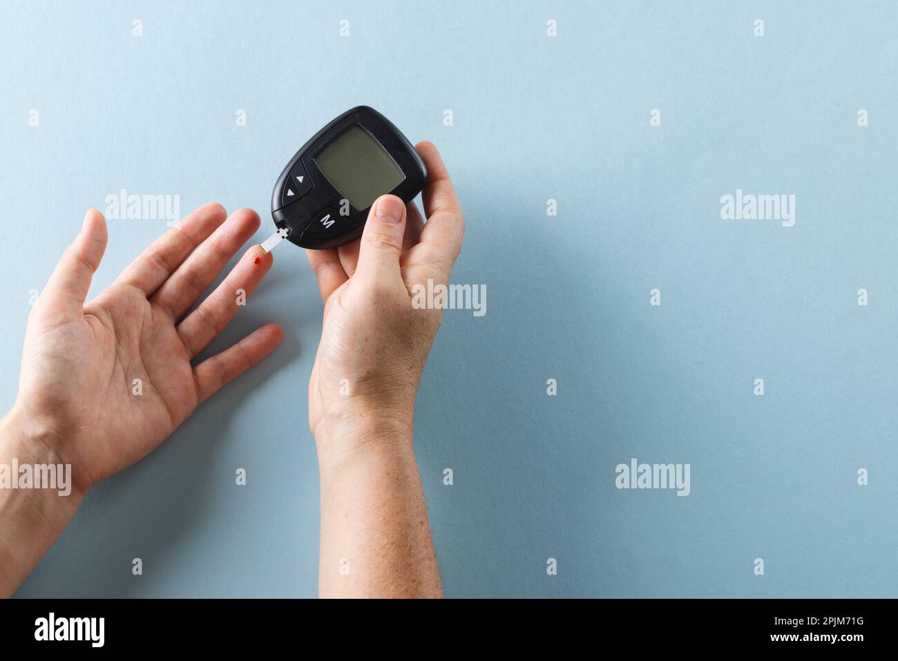 Hands of caucasian woman taking blood sugar reading with glucometer, on ...