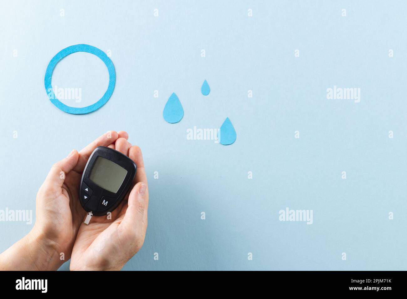 Hands of caucasian woman holding glucometer over blue drops and ring on ...