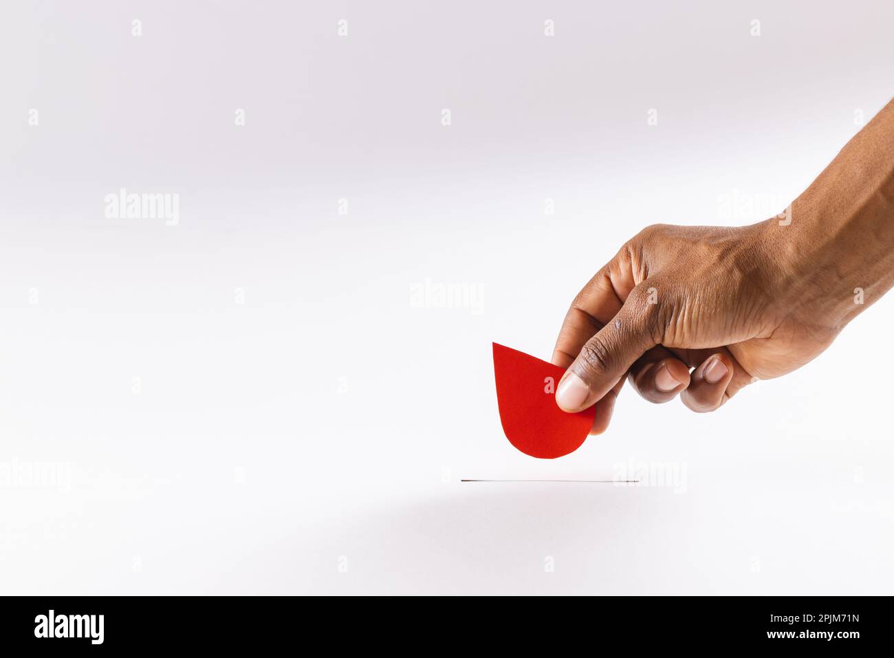 Hand of biracial man holding blood drop above slot, on white background ...