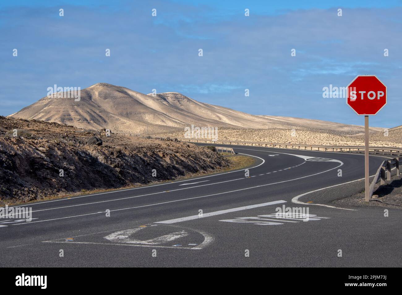 Road with a curve up the hill. Traffic sign Stop. Mountain in the ...