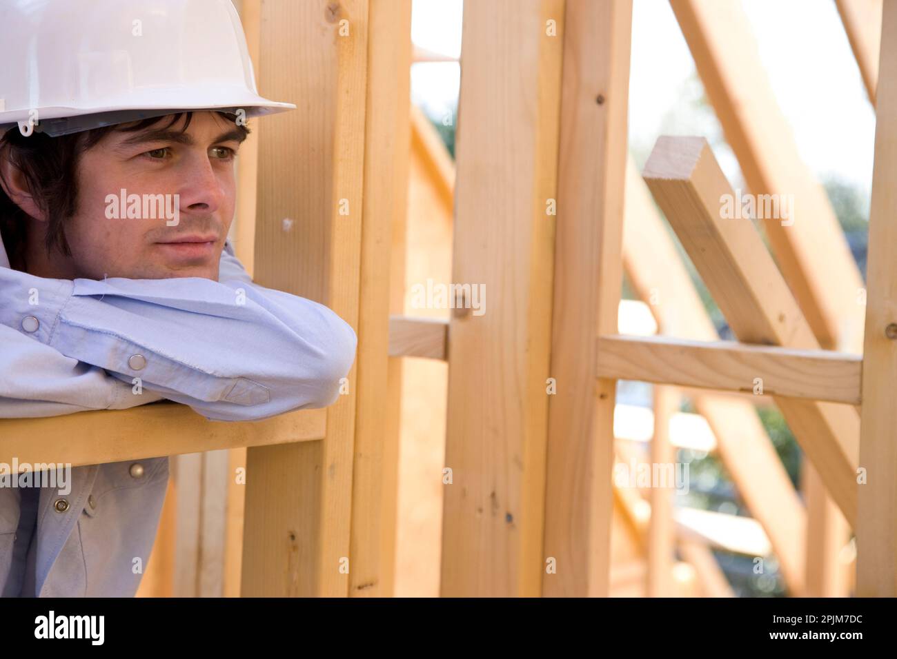 Portrait of young man leaning against beam in construction site Stock ...