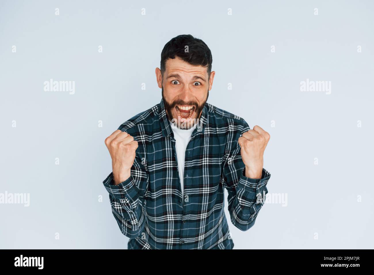 Celebrating success. Young man in casual clothes standing indoors in ...