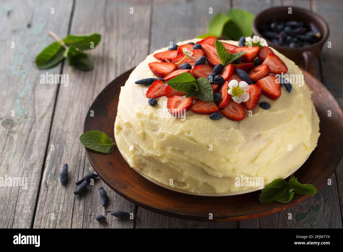 Homemade cake with custard and strawberries and honeysuckle on a rustic ...
