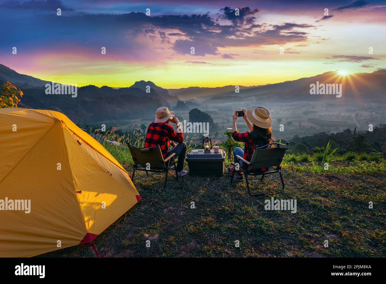 Romantic couple camping outdoors and taking photos with camera while ...