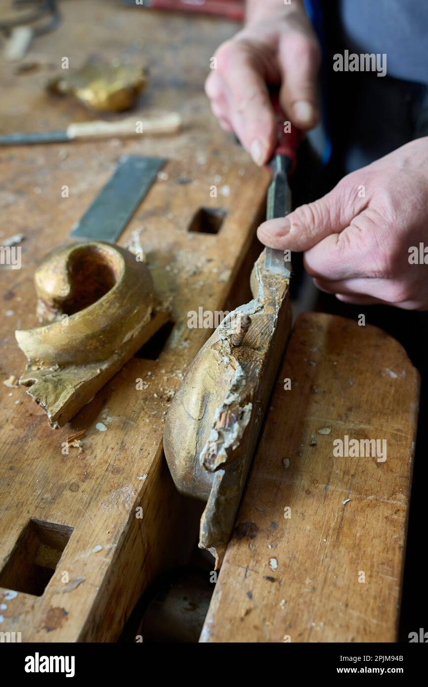 A skilled craftsman is carefully chiseling a piece of wood, creating a ...