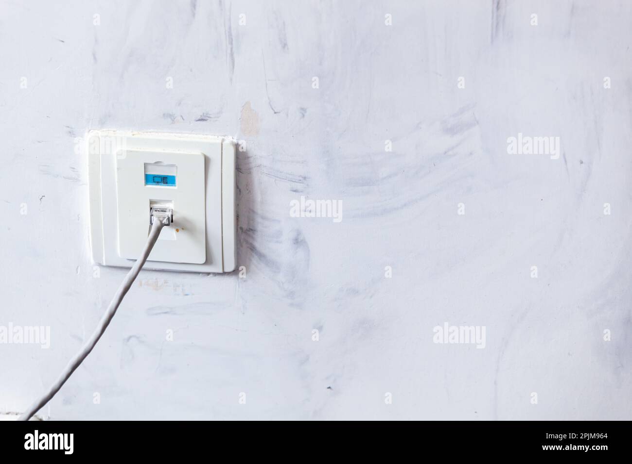 A smeared gray wall with an Internet outlet and dark translucent ...