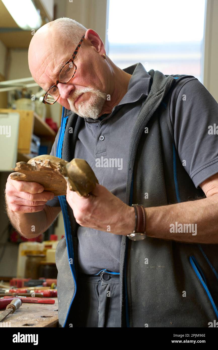 A skilled craftsman is carefully chiseling a piece of wood, creating a ...