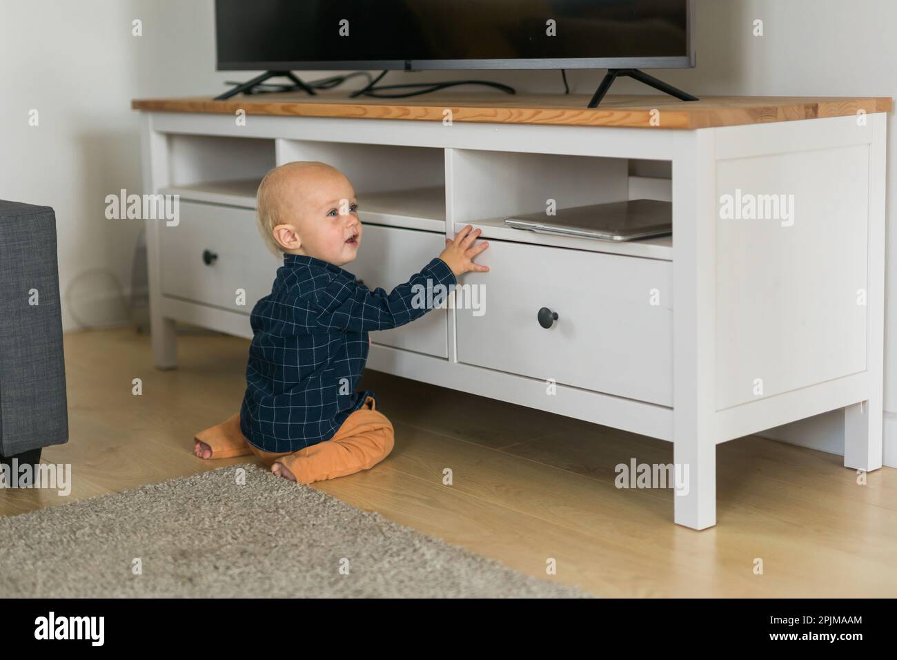 Toddler baby boy open cabinet drawer with his hand. Child explore what ...
