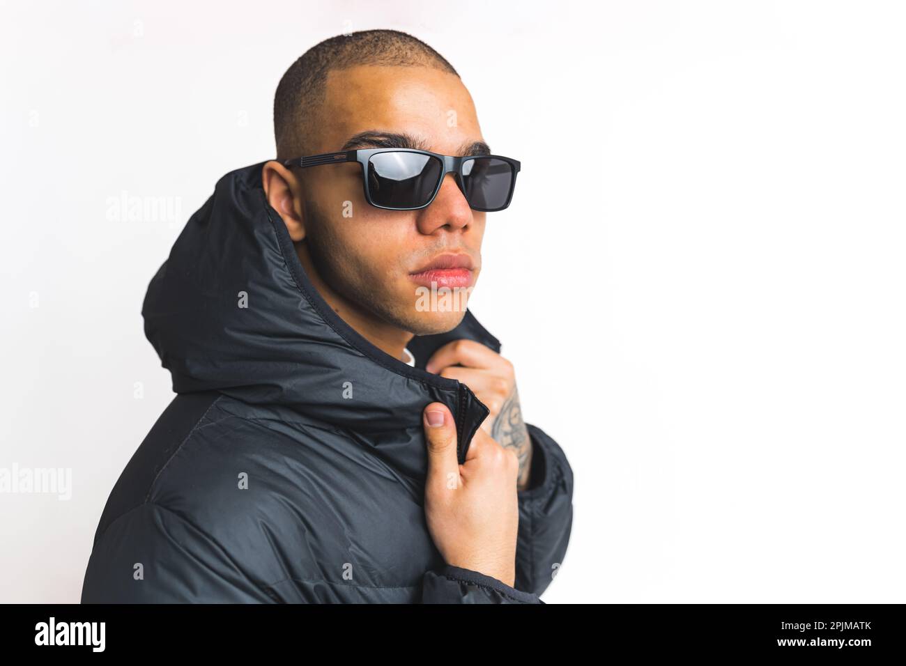 Serious confident male model in sunglasses and black puffer jacket ...