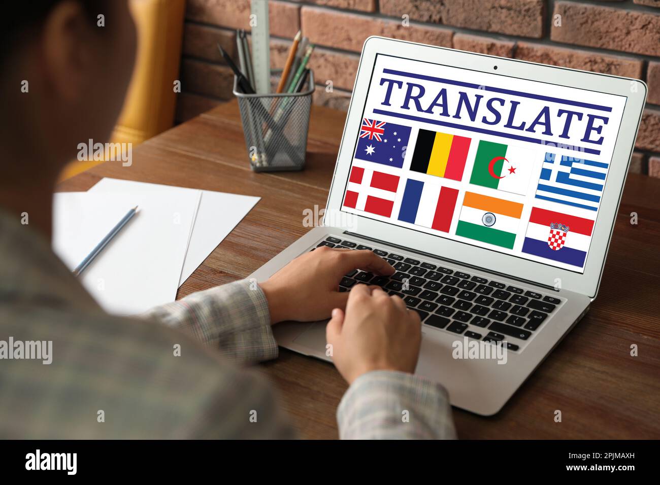 Translator using modern laptop with images of different flags on screen ...