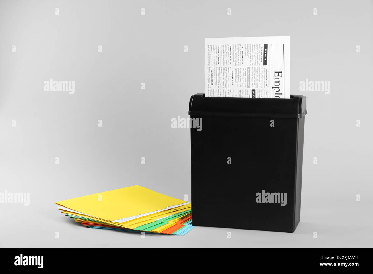 Shredder with sheet of paper and colorful folders on grey background ...