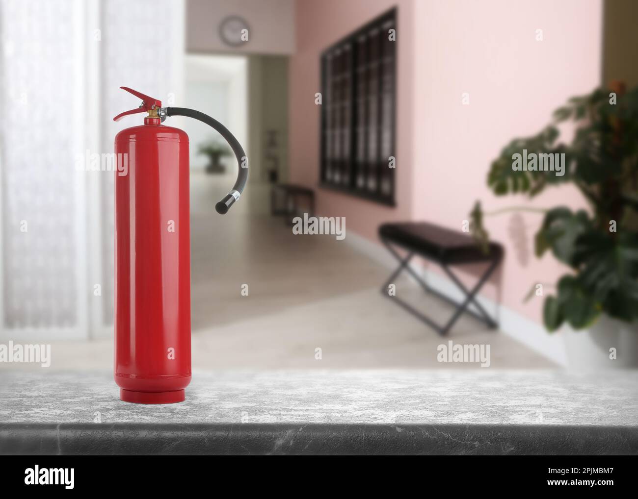 Fire extinguisher on stone table in office corridor. Space for text ...