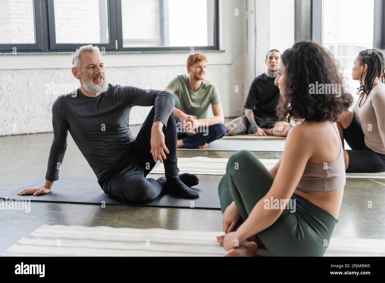Positive mature man talking to middle eastern woman in yoga class,stock ...