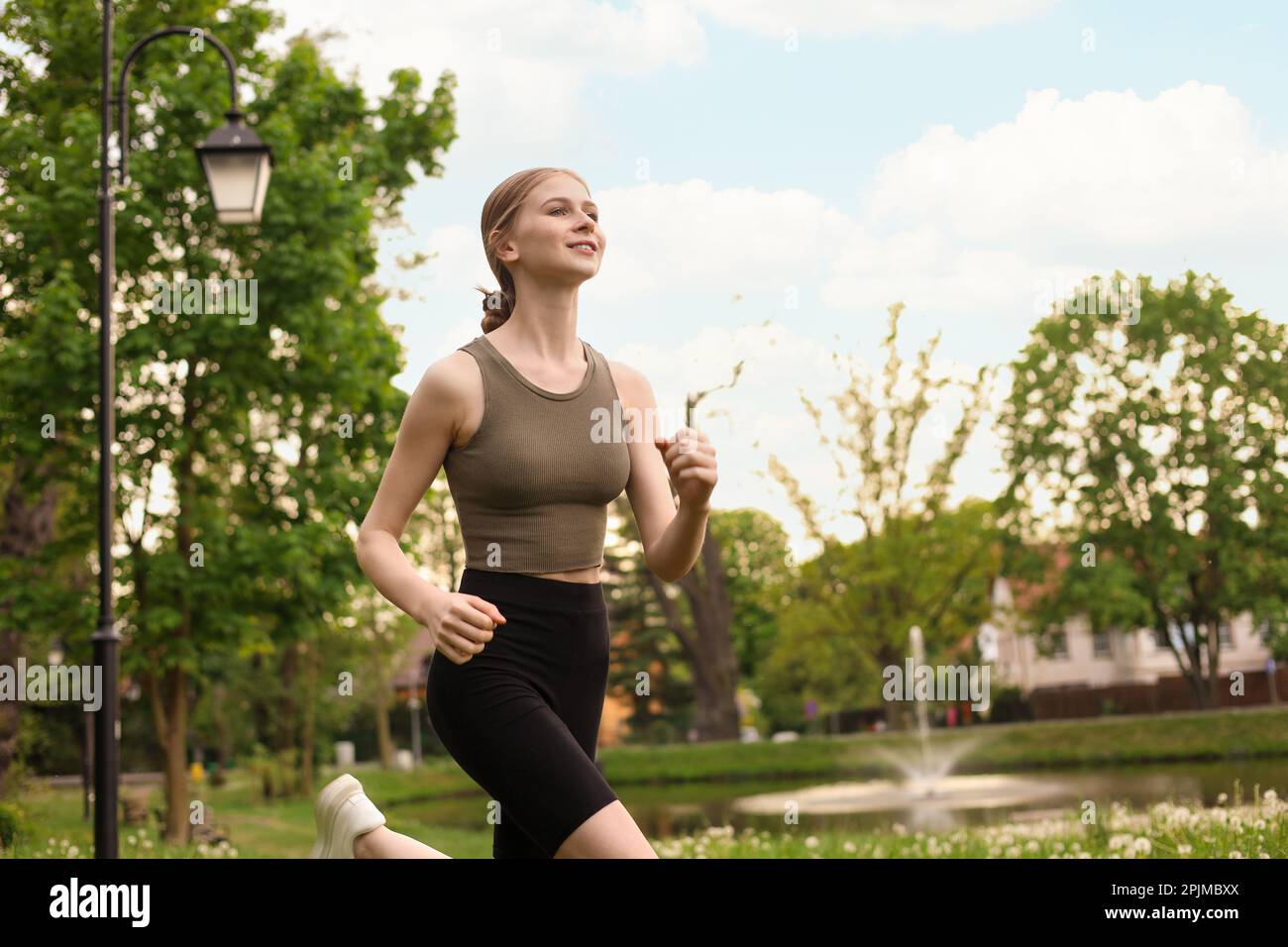 Teenage girl jogging around park in morning. Space for text Stock Photo ...