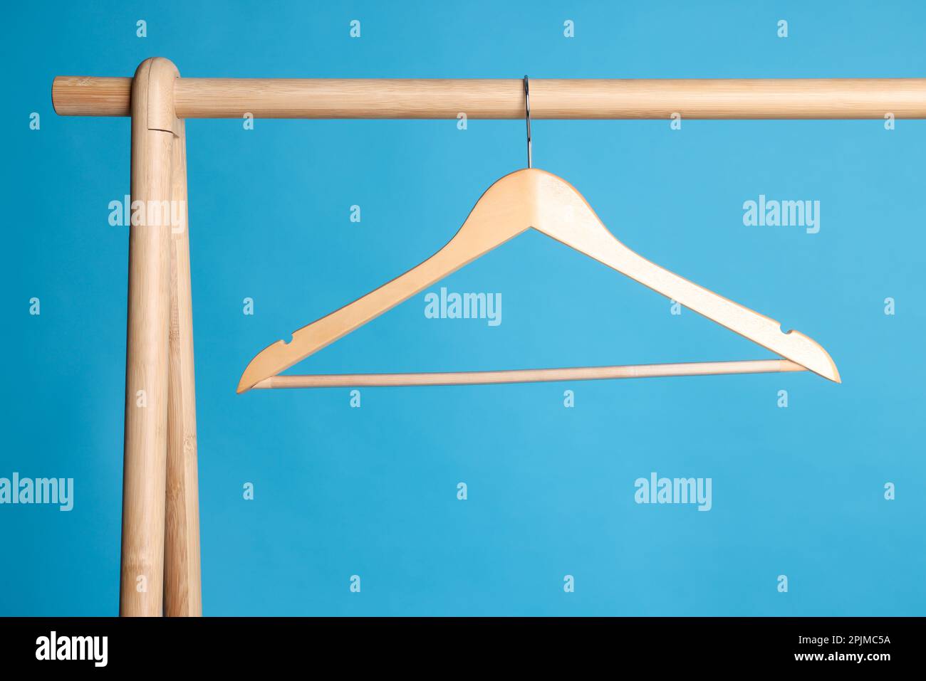 Empty clothes hanger on wooden rack against light blue background Stock ...