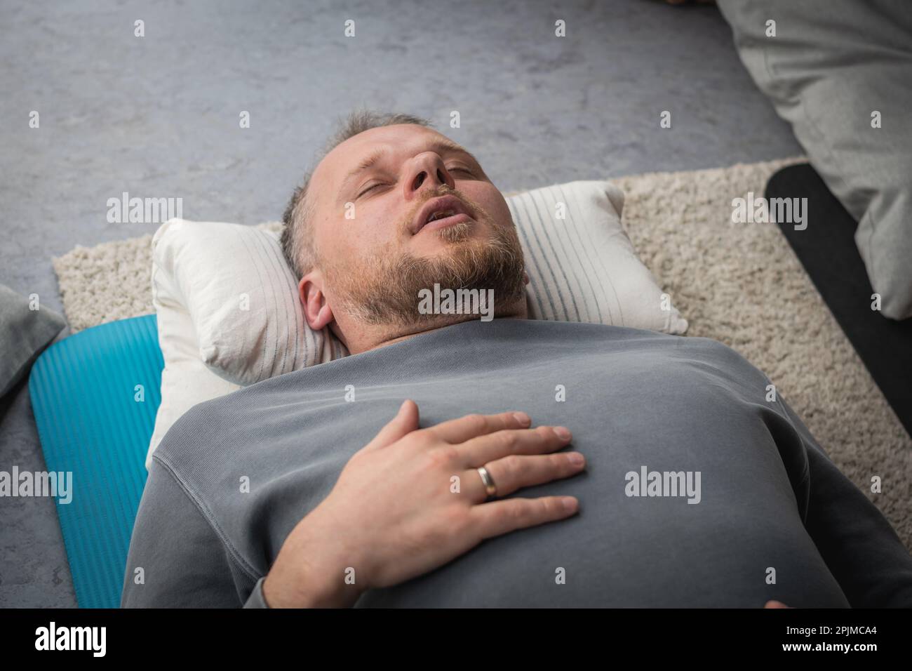Boy during a yoga class lying on a mat, breathing and meditating with ...