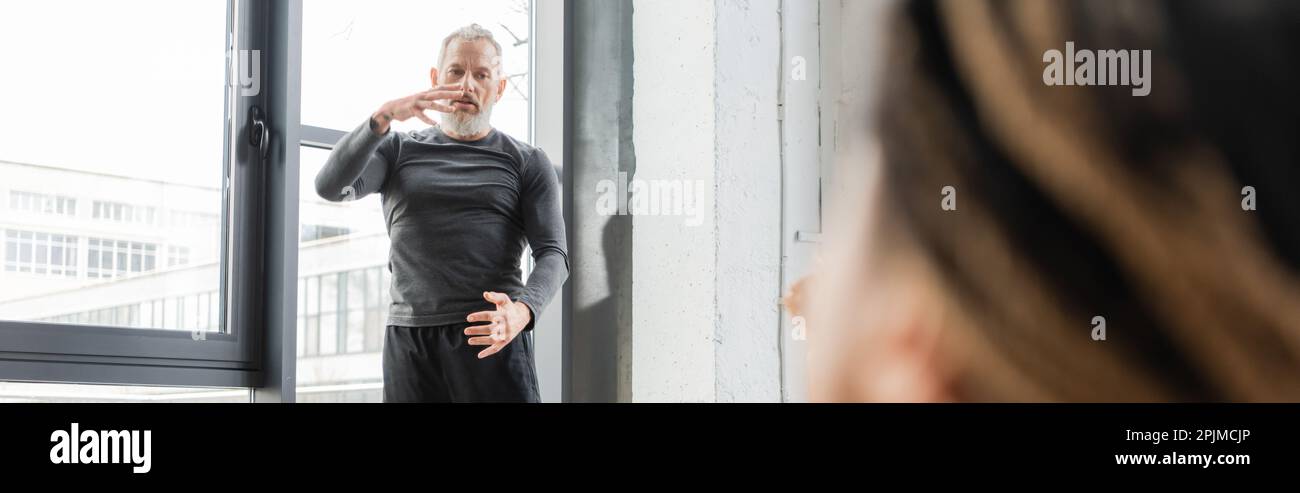 Mature coach explaining asana to blurred african american woman in yoga ...