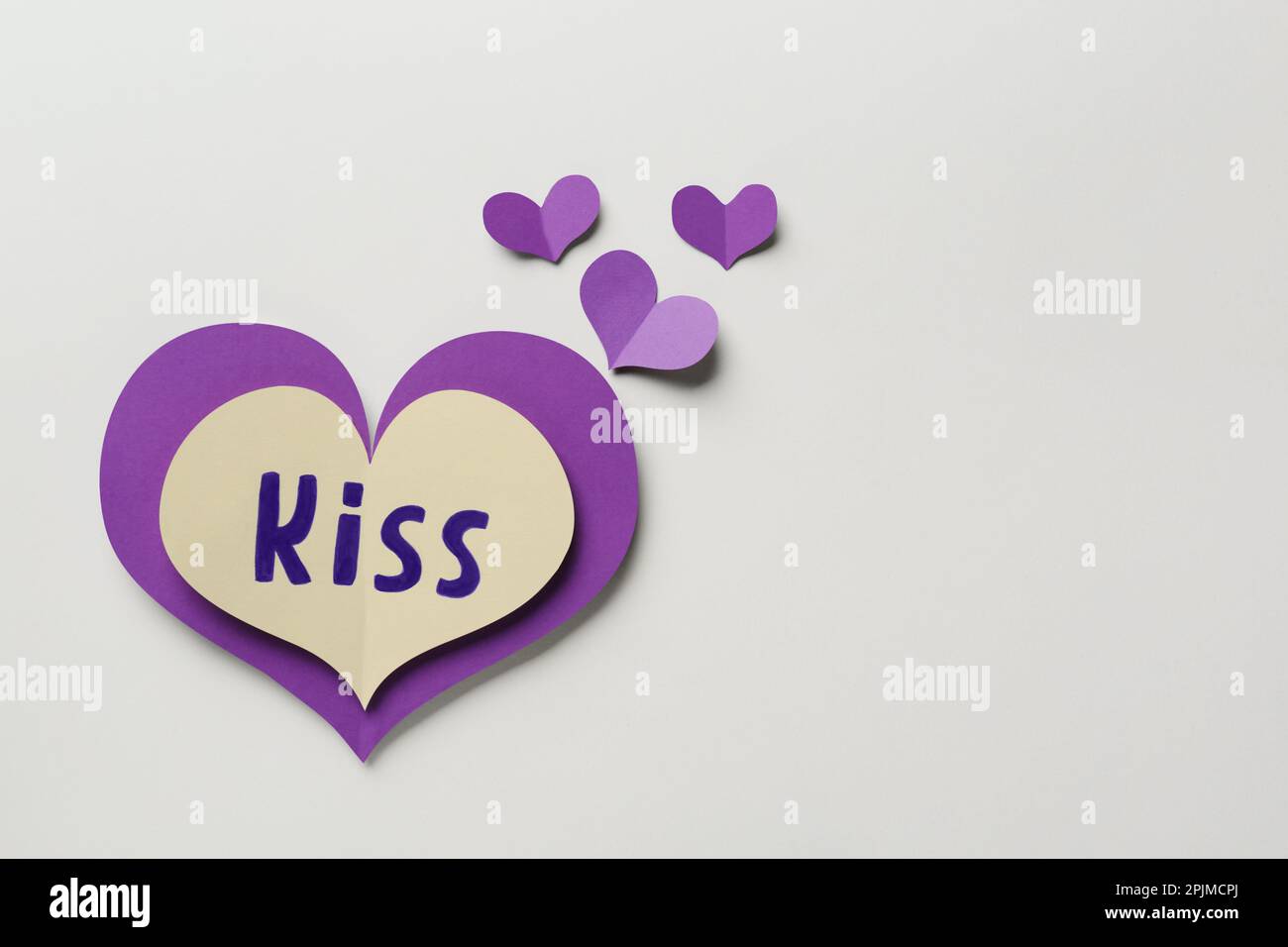 Paper hearts and one with word Kiss on beige background, flat lay ...