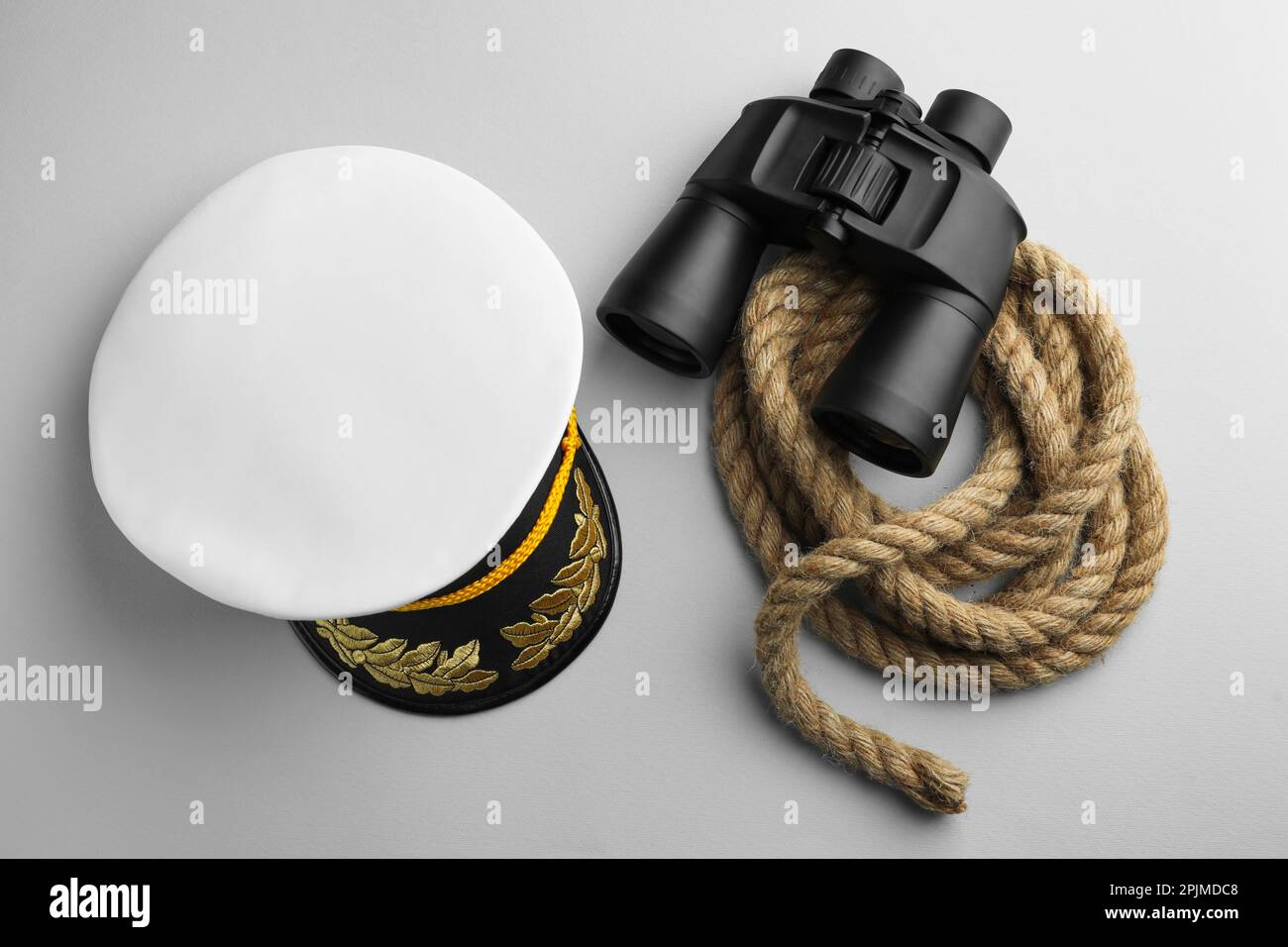 Peaked cap, rope and binoculars on light grey background, flat lay ...