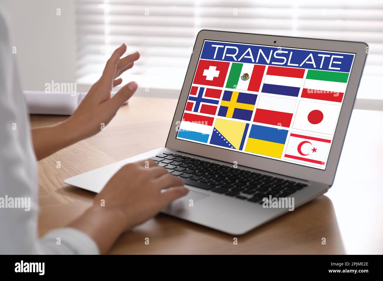 Translator using modern laptop with images of different flags on screen ...