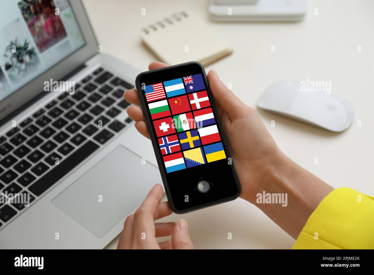 Translator using smartphone with images of different flags on screen at ...