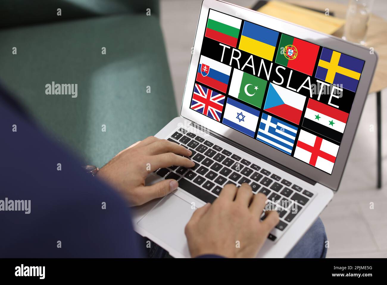 Translator using modern laptop with images of different flags on screen ...