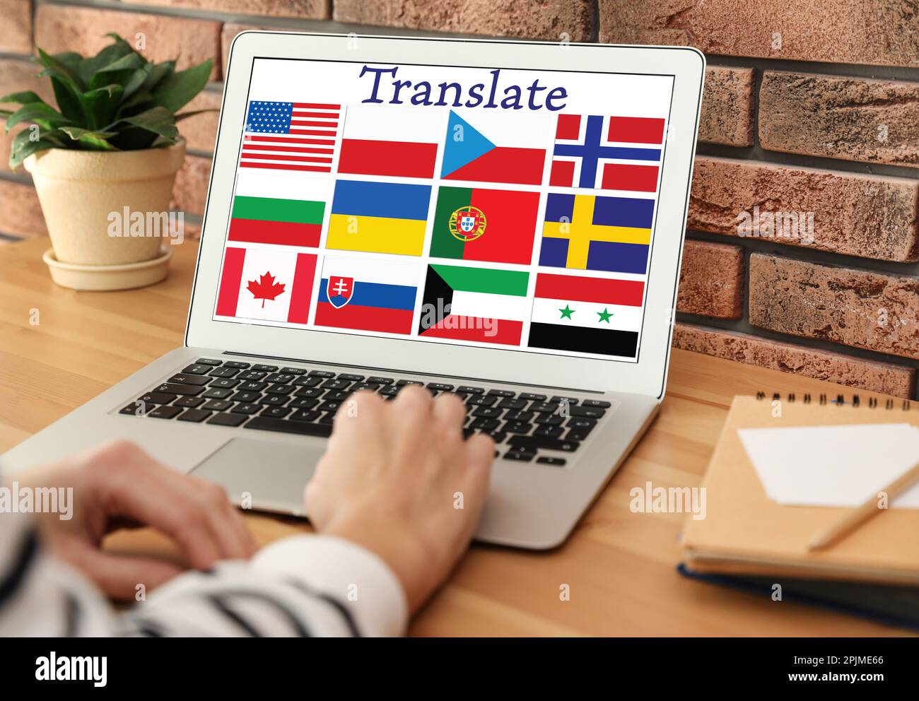 Translator using modern laptop with images of different flags on screen ...