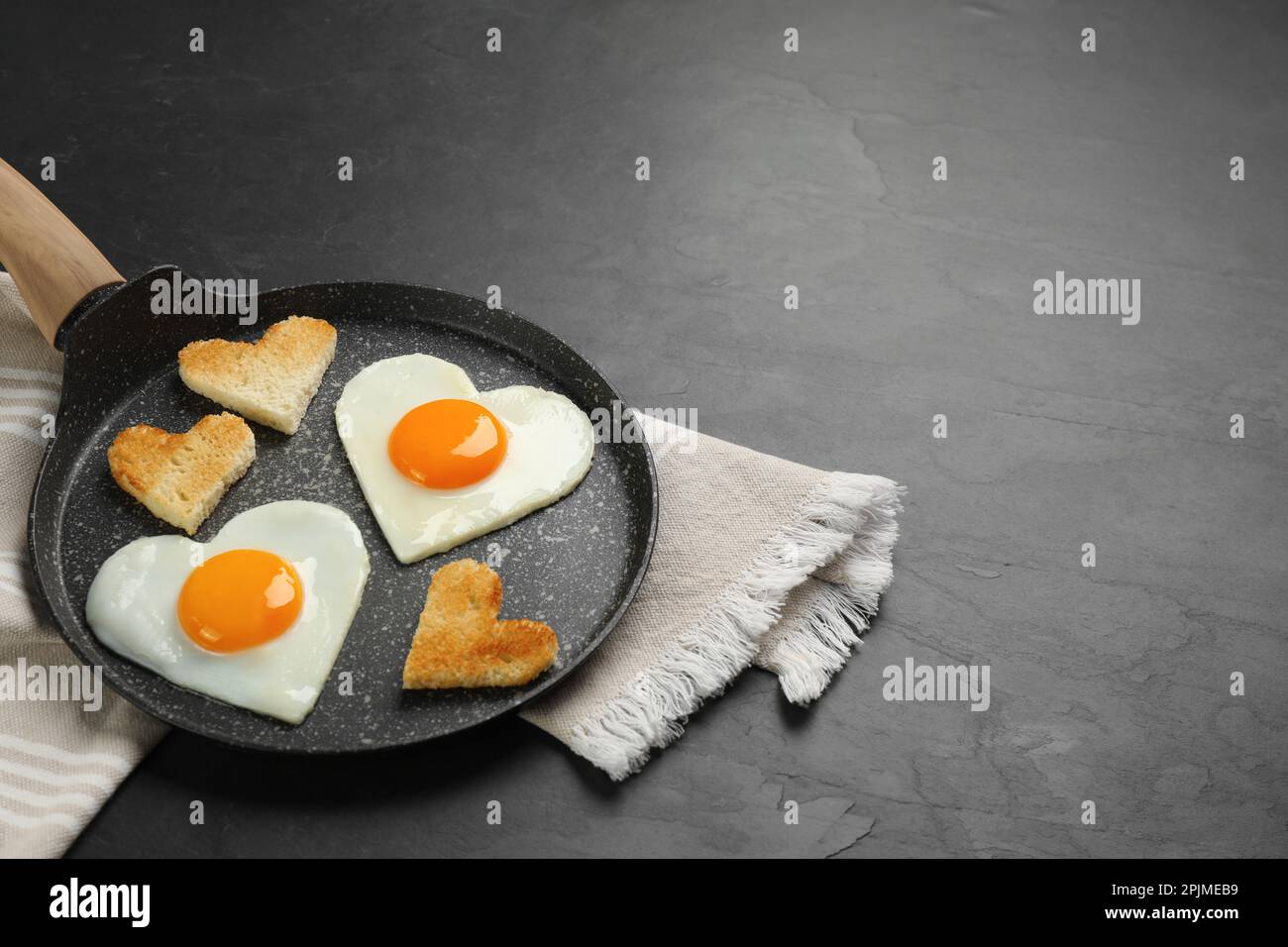 Heart shaped fried eggs and toasts in frying pan on grey table, space for text Stock Photo - Alamy