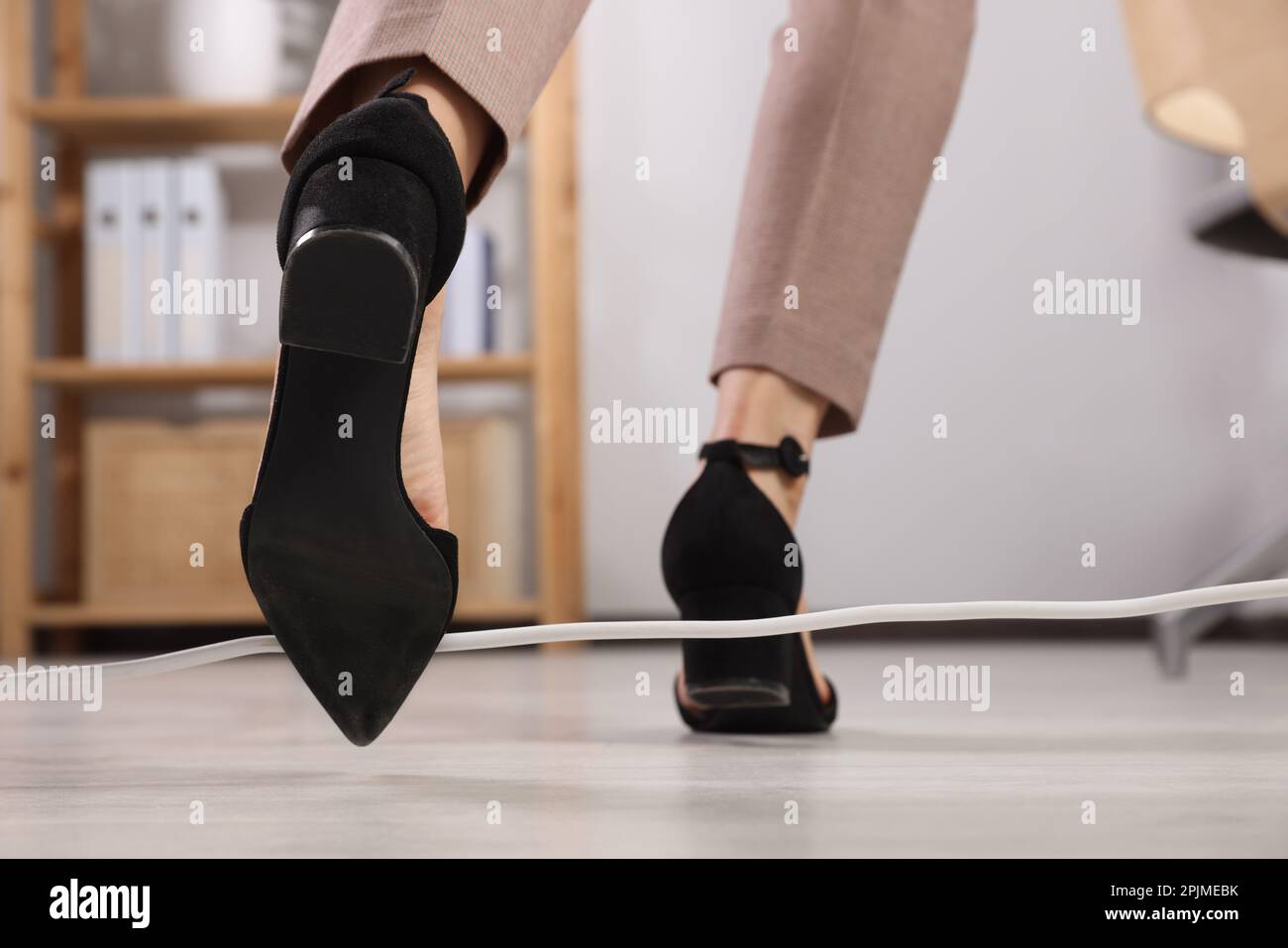 Woman tripping over cord in office, closeup Stock Photo - Alamy