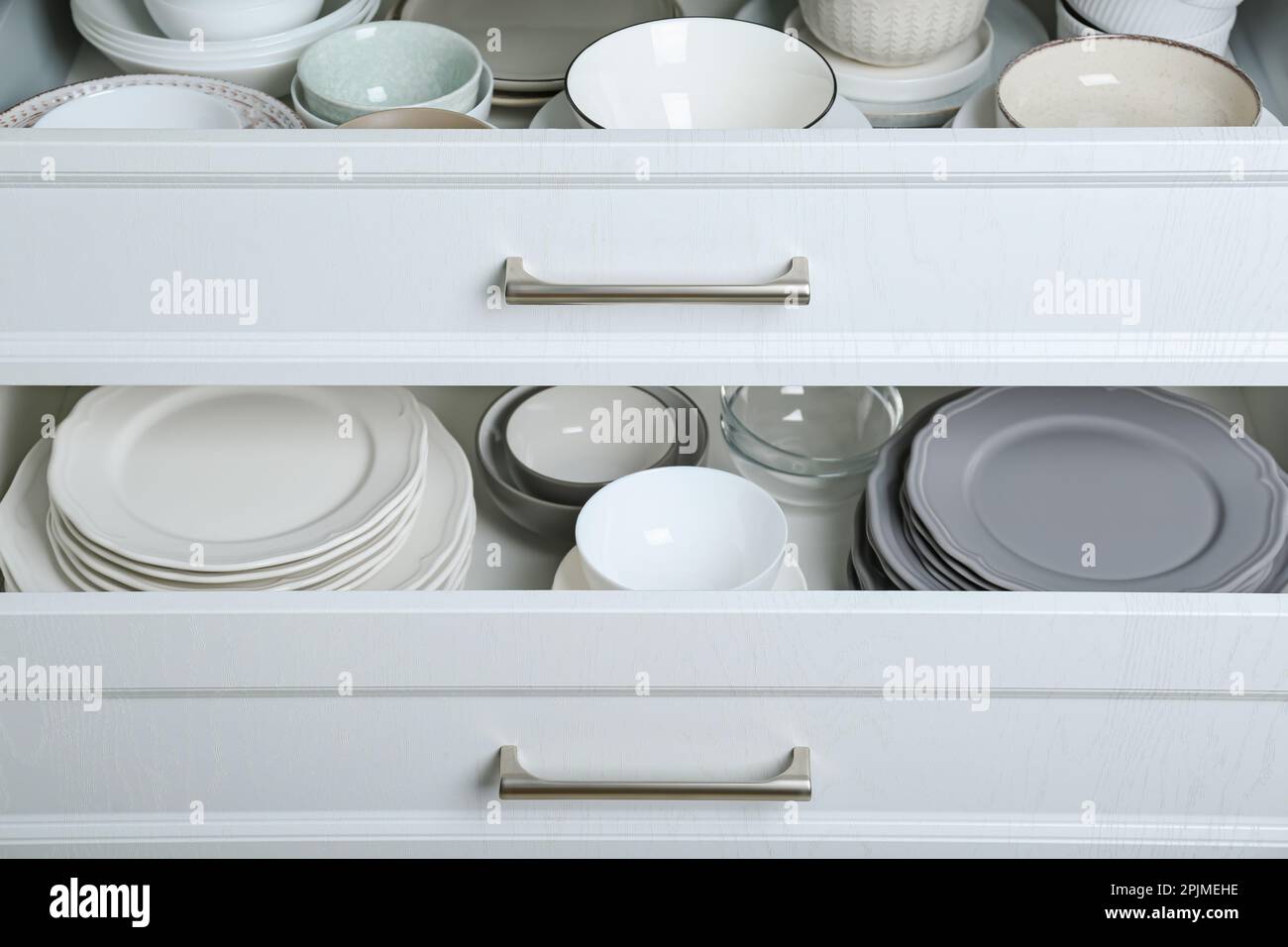 Open drawers with different plates and bowls, closeup Stock Photo - Alamy