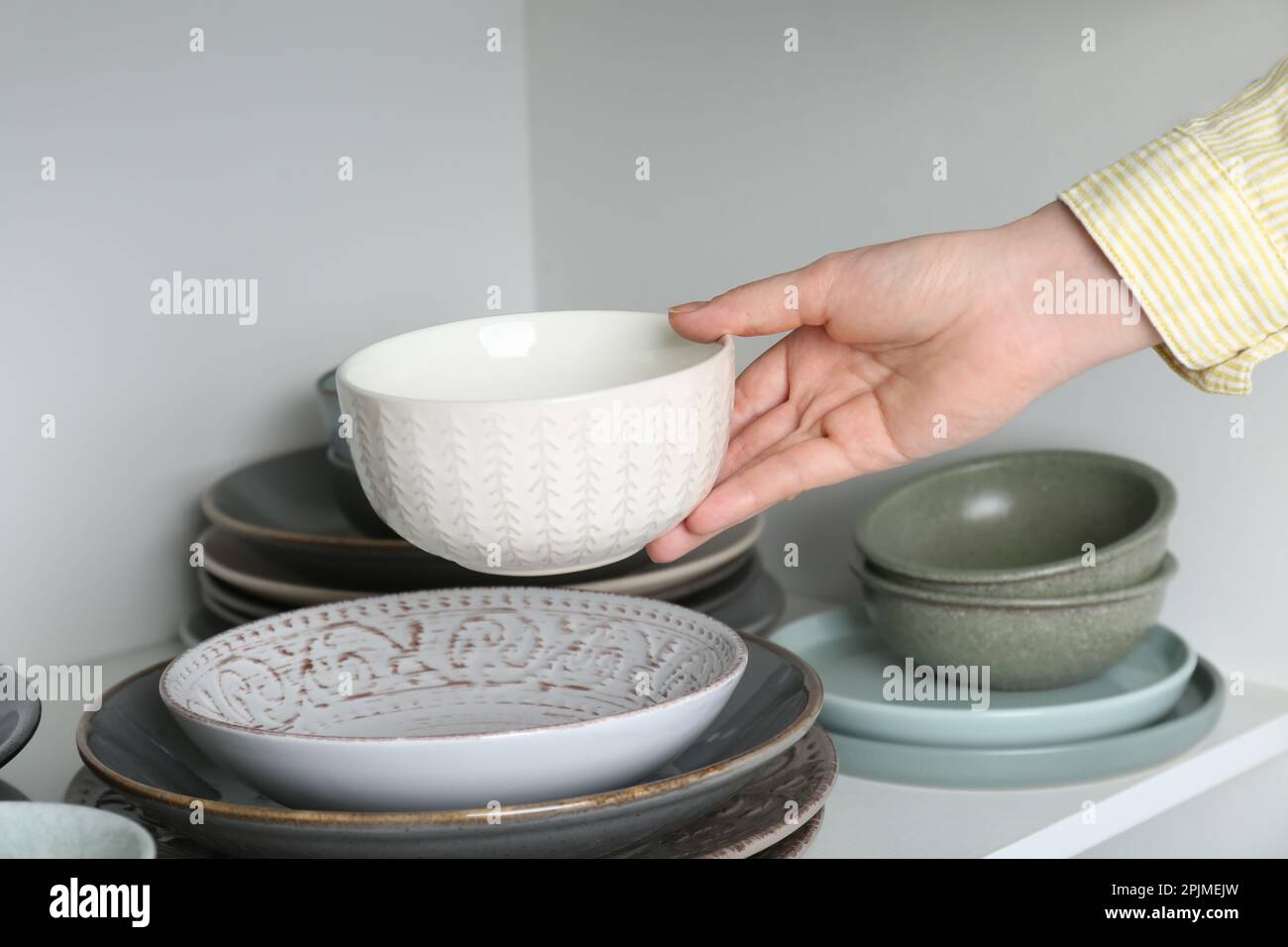 Woman taking ceramic bowl from shelf, closeup Stock Photo - Alamy