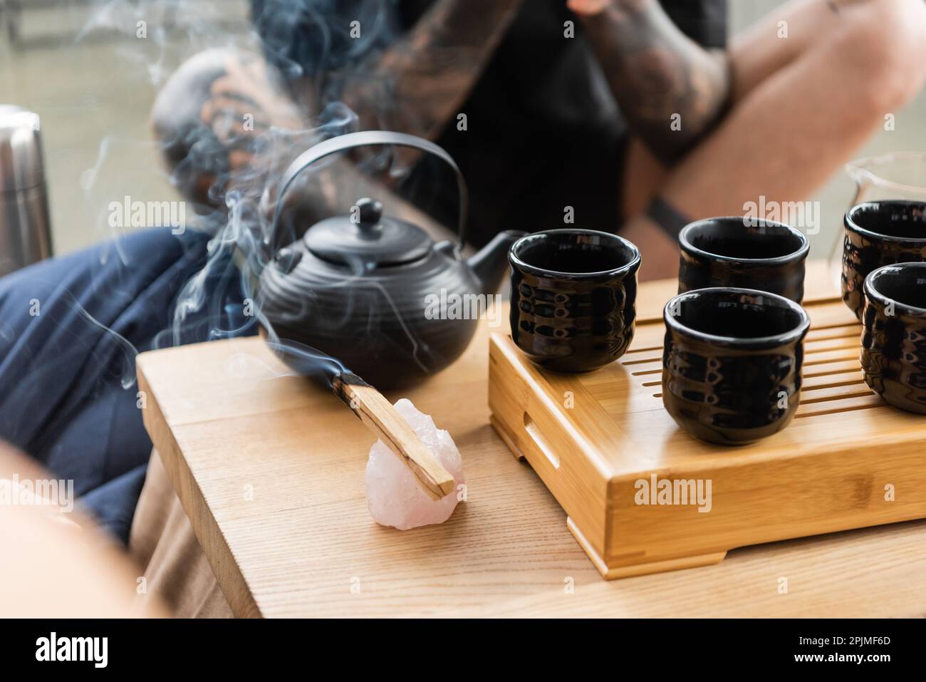 burning Palo Santo stick near traditional Chinese teapot and cups in ...