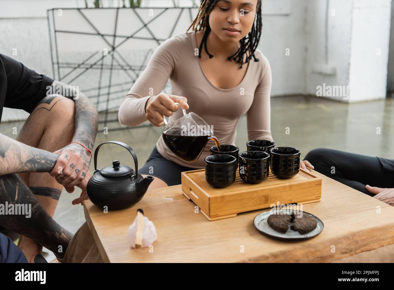 african american woman with dreadlocks pouring puer into traditional ...