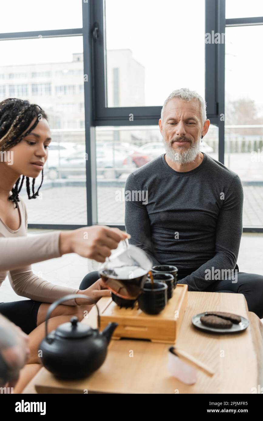 african american woman with dreadlocks pouring puer into traditional ...