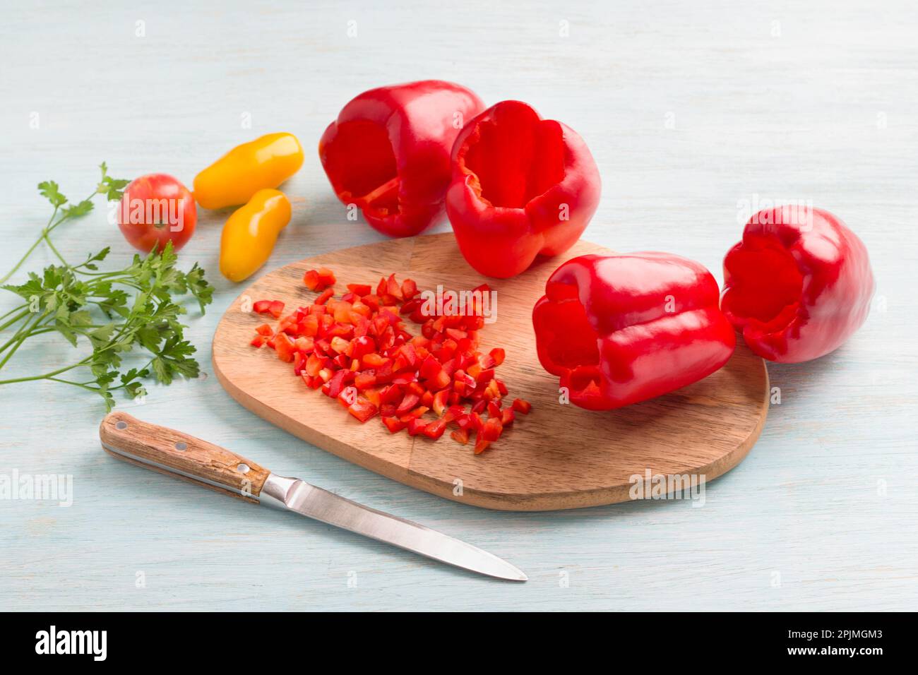 Wooden board with chopped red bell peppers, whole peeled bell peppers ...