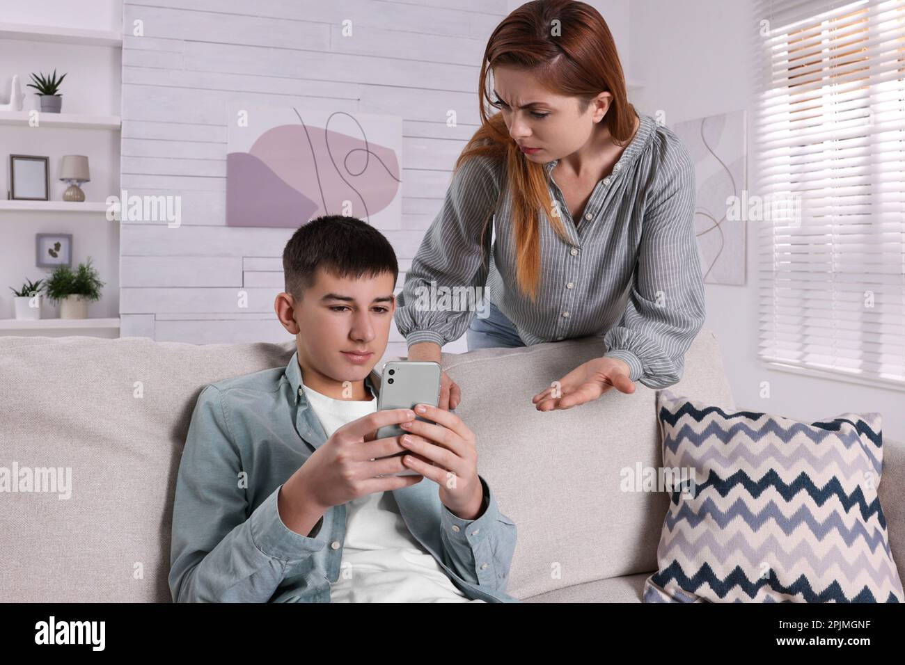 Mother scolding her son while he using smartphone at home. Teenager ...
