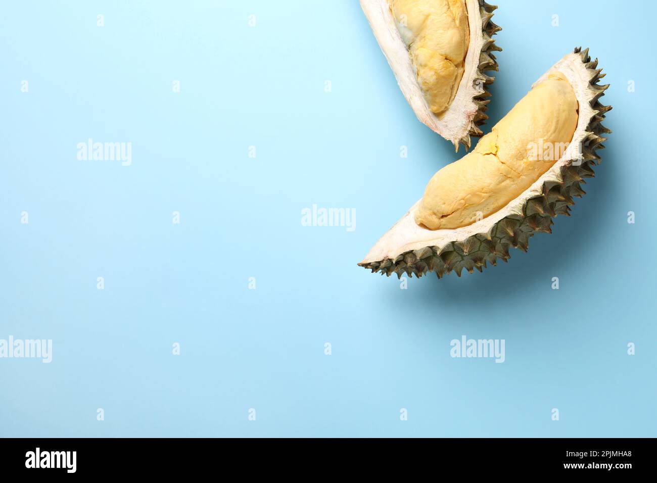 Pieces of fresh ripe durian on light blue background, flat lay. Space ...